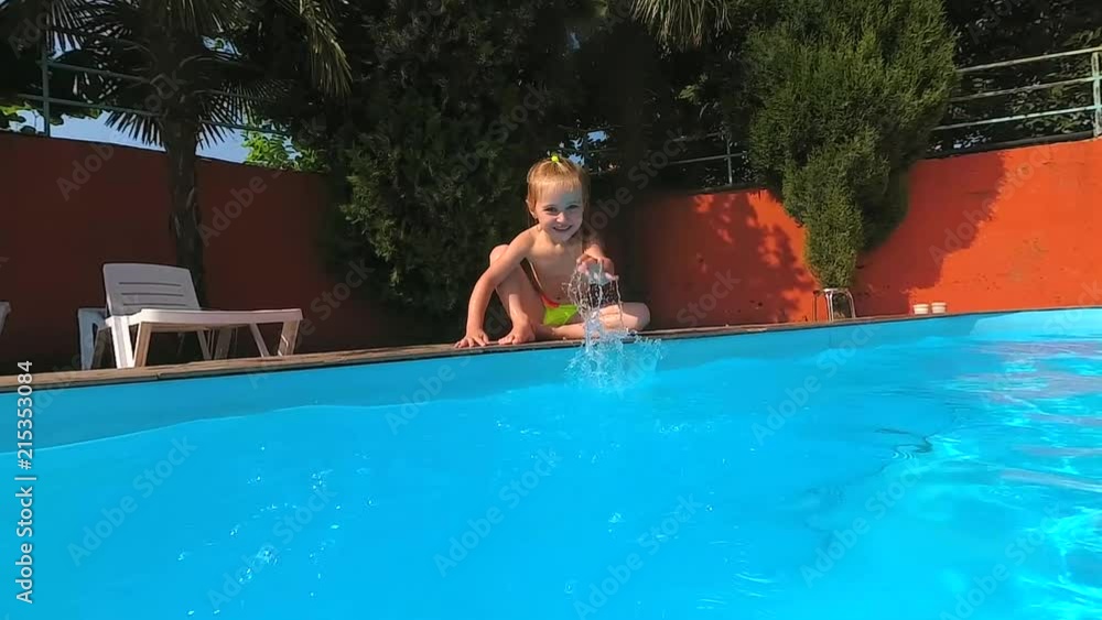 Happy little girl splashing water in the swimming pool. Little child ...