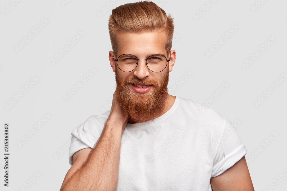 Cheerful ginger male with thick beard and mustache, looks mysteriously ...