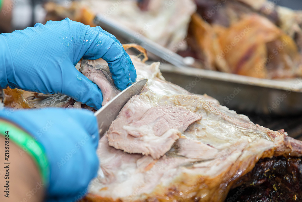 Cutting the mutton hulk fried on a grill for the Uzbek pilaf. Male ...