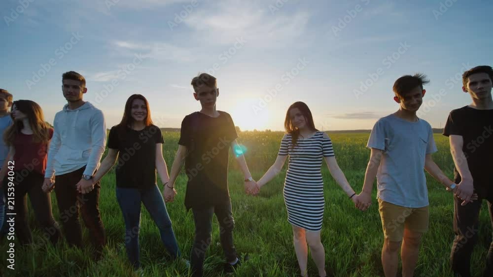 Vidéo Stock Silhouettes of nineteen friends holding hands on a sunset ...