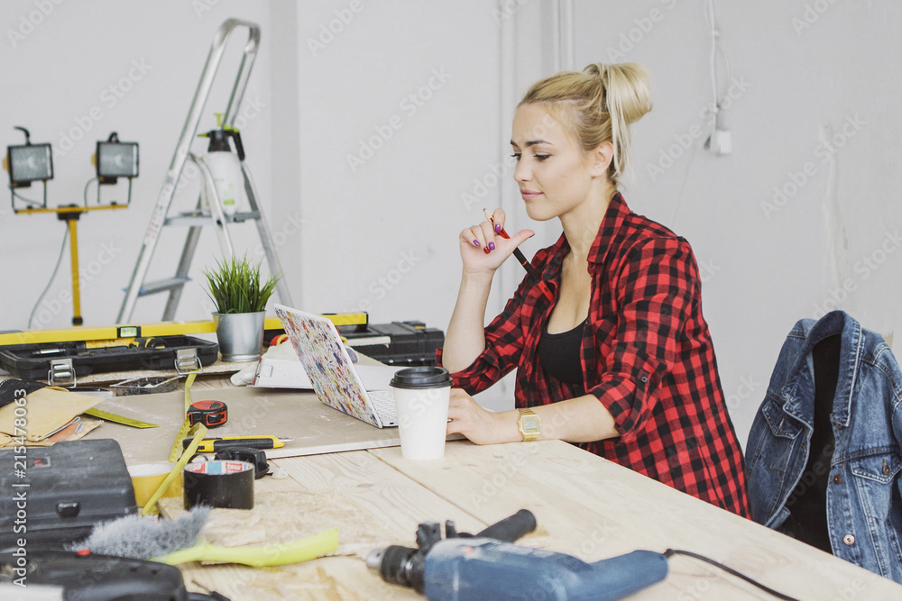 Beautiful young woman in checkered shirt sitting at wooden workbench ...