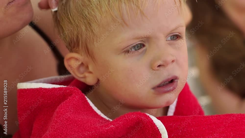 Mom hugs her cute little son wrapped in a red towel on the beach in the ...