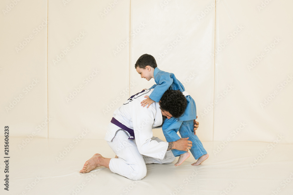 Male karate instructor training little child in dojo or jiu-jitsu at ...