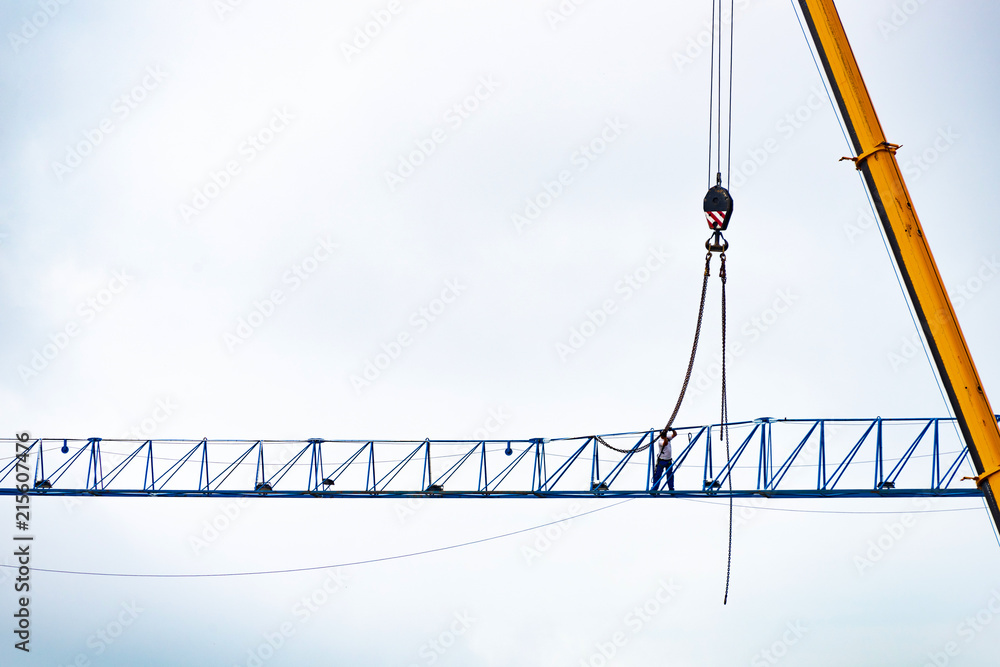 Setting up a blue tower crane in the construction site. Worker is ...