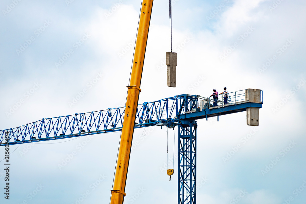Setting up a blue tower crane in the construction site. Workers are ...