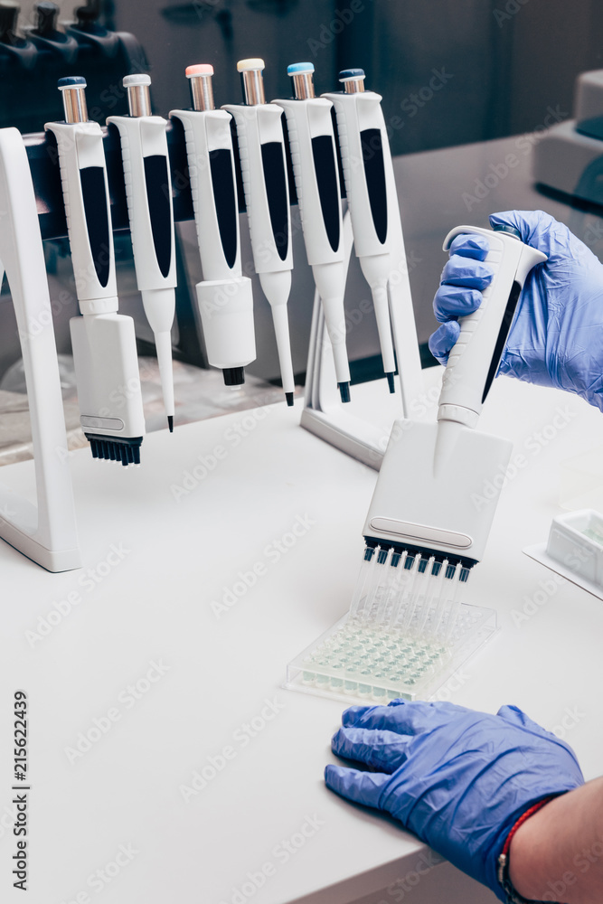 partial view of scientist using multichannel pipette at working table ...