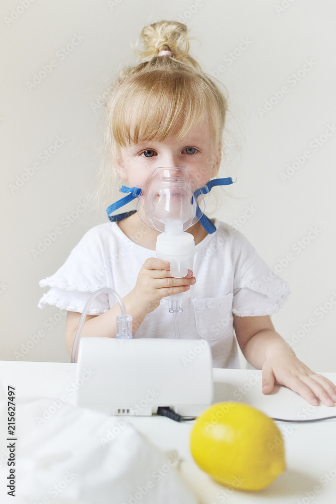 Little girl in a mask for inhalations, making inhalation with nebulizer ...