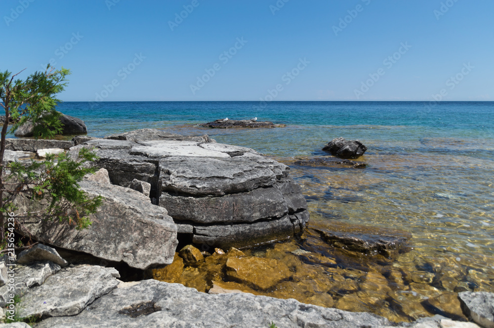 Lake Huron shoreline blue green water and limestone rocks along the ...