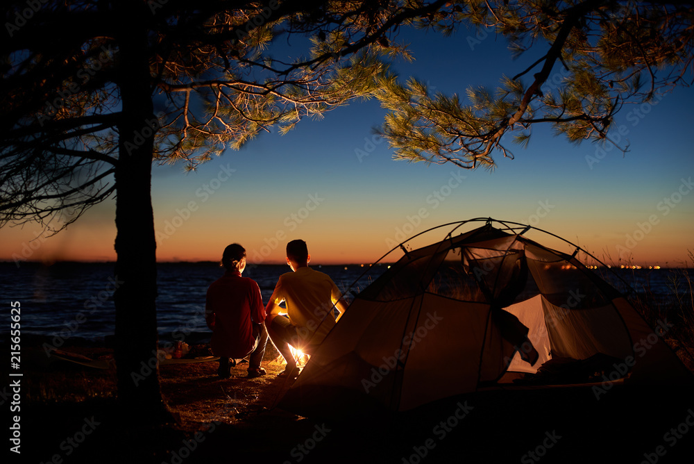 Night camping at lake. Tourist tent and back view of young couple, boy ...
