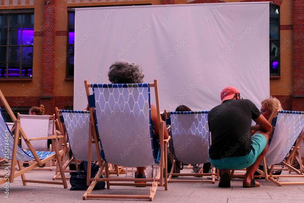 People are sitting on the sun loungers in the open-air cinema. Stock ...