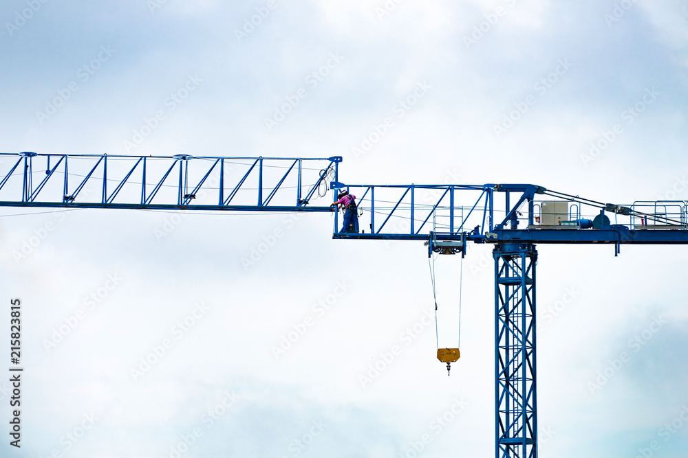 Setting up a blue tower crane in the construction site. Workers are ...