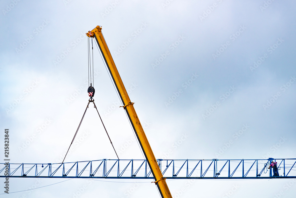 Setting up a blue tower crane in the construction site with a heavy ...