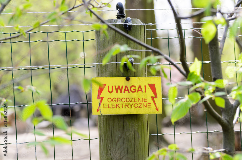 Warning sign with a live fence in polish language (uwaga ogrodzenie ...