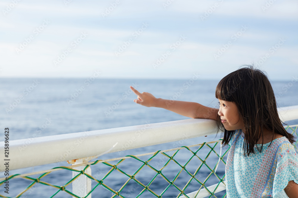 Asian little girl lying on the railing. On the cruise ship, the sea ...