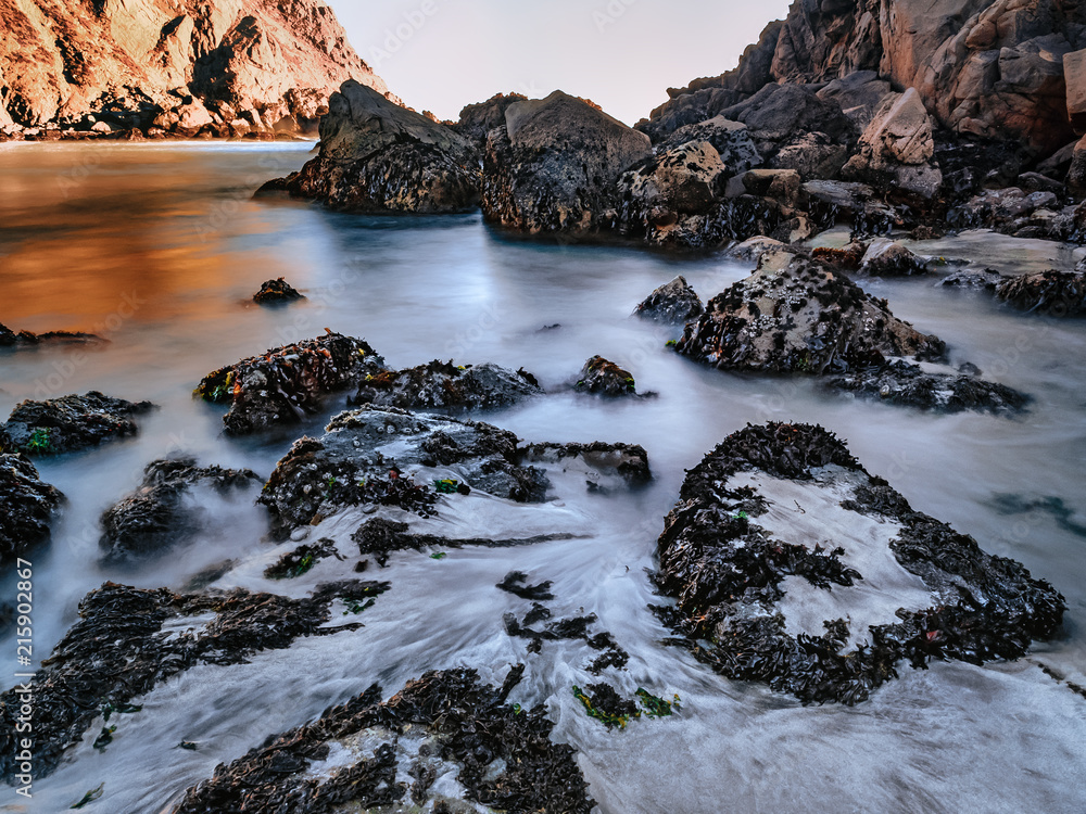 Long-exposure photography of scenic coastal rocks covered with algae at ...