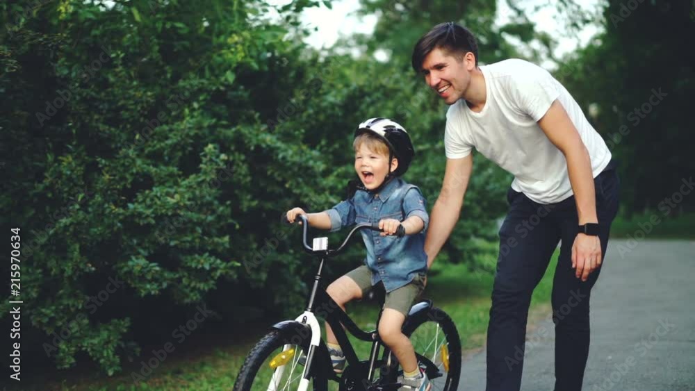 Slow motion of excited boy riding bicycle and laughing while his ...