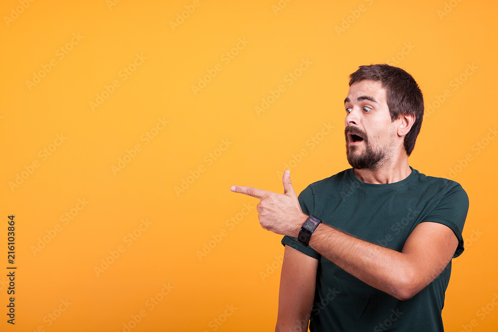 Expressive shocked man pointing at his right with his mouth open on ...