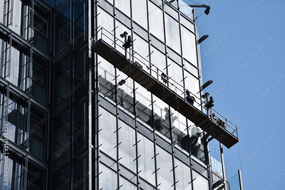 Construction workers on a suspended platform on a skyscraper Stock ...