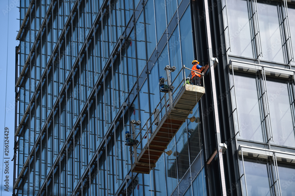 Construction workers on a suspended platform on a skyscraper Stock ...