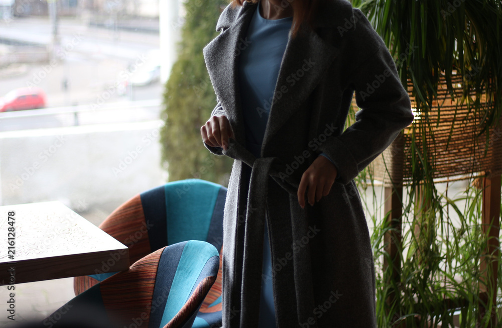 the girl takes off her gray coat, under which a blue dress, untying the ...