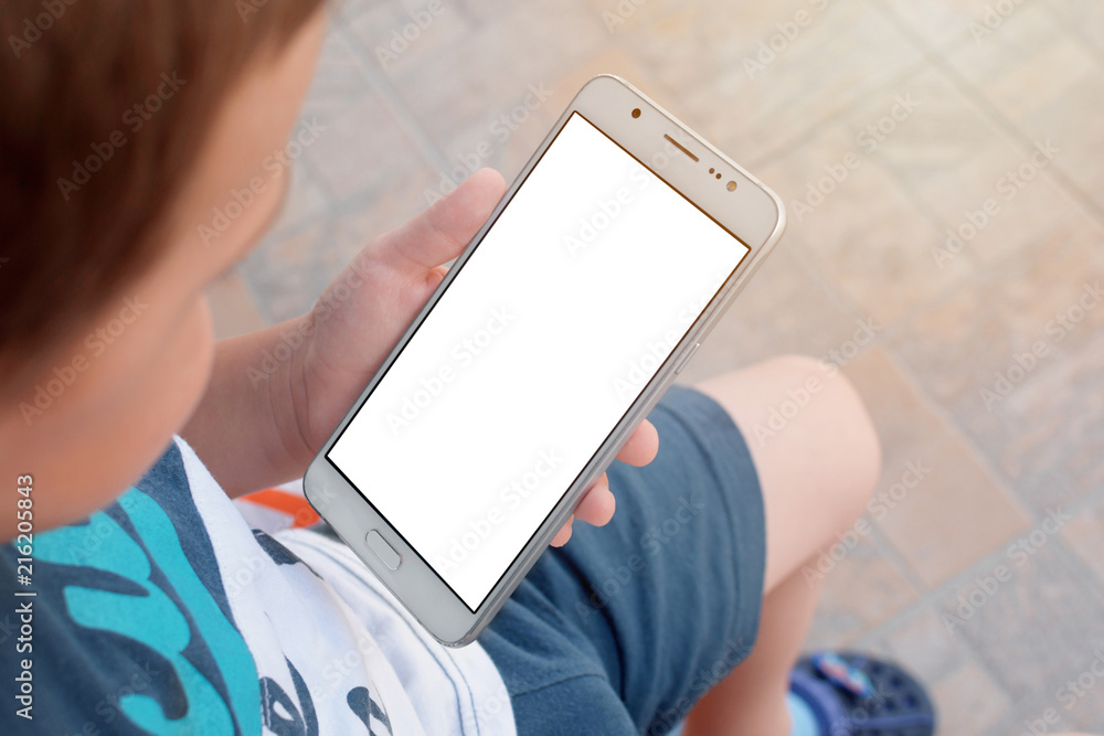 Little boy holding smartphone with isolated screen, top view. Kid play ...