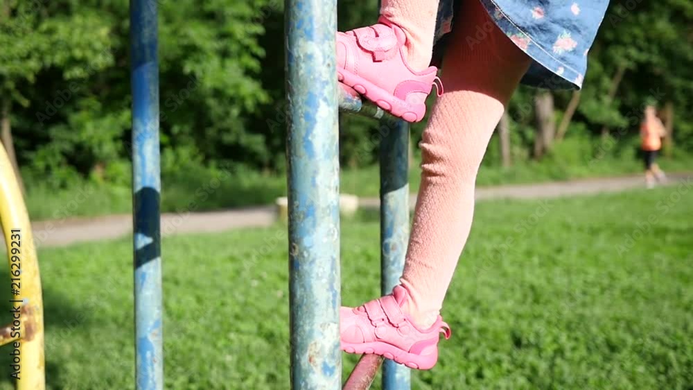 Little kid girl legs climbing a gym ladder on a playground in a park ...