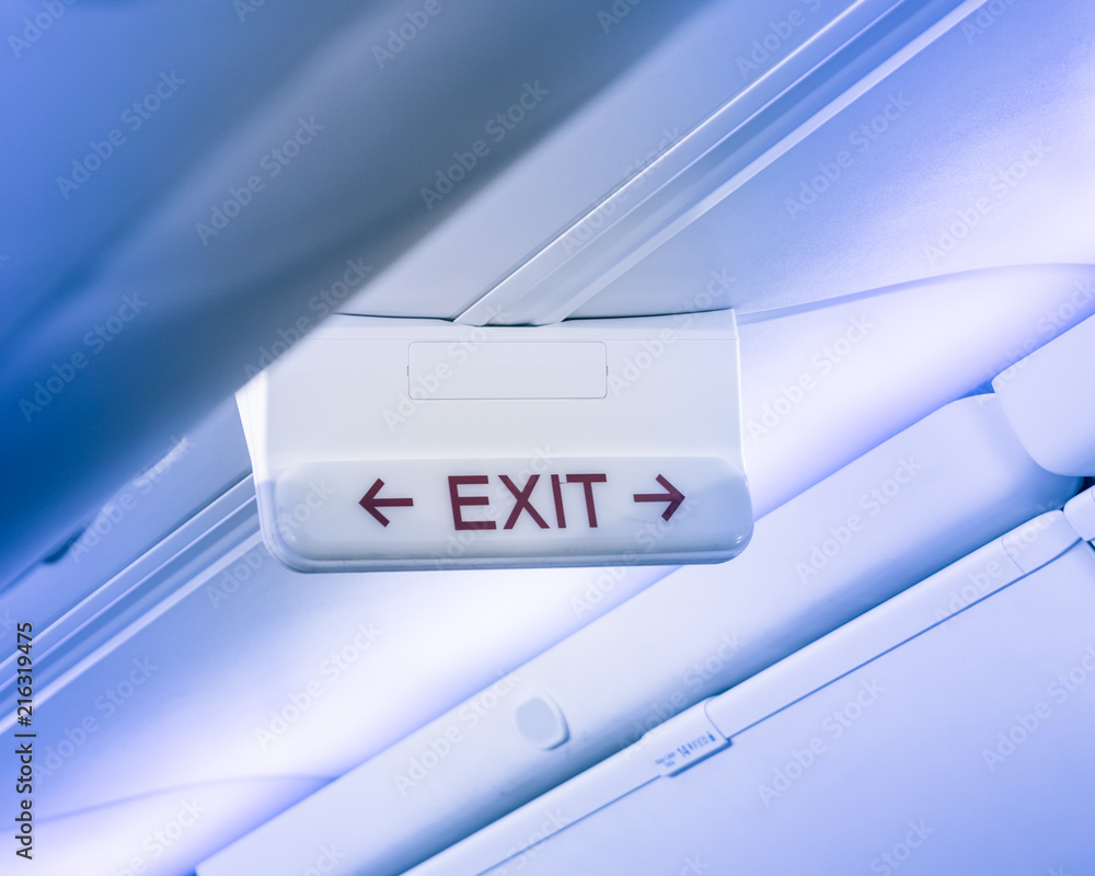 Vintage tone emergency exit sign with red arrow on ceiling of airplane ...