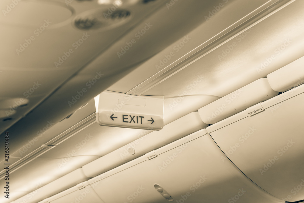 Vintage tone emergency exit sign with red arrow on ceiling of airplane ...