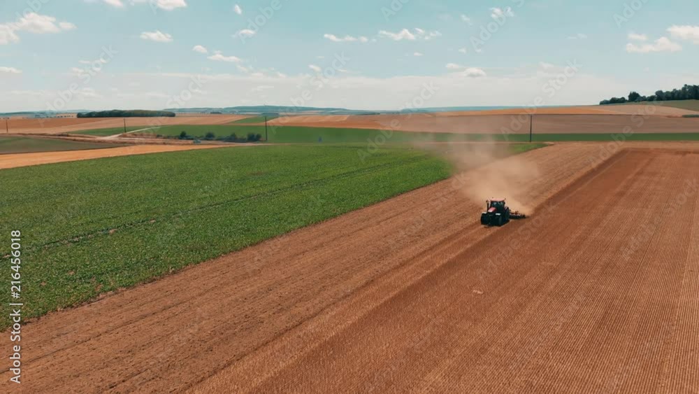 Aerial drone view of red tracor working in wheat field. Agriculture and ...