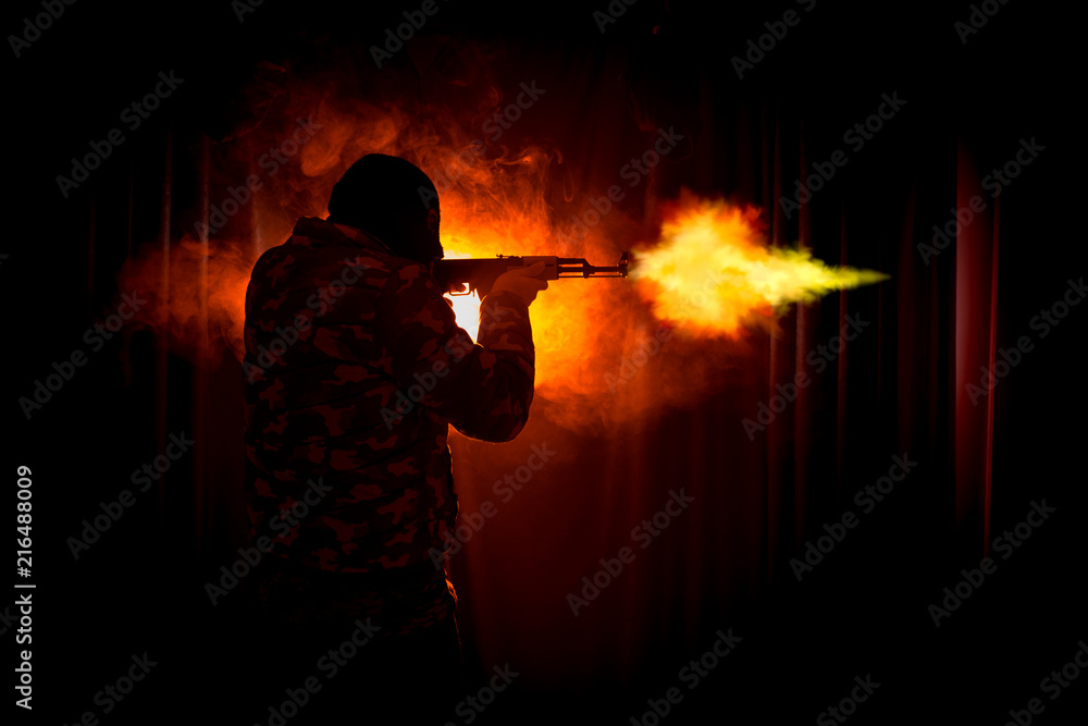 Silhouette of man with assault rifle ready to attack on dark toned ...