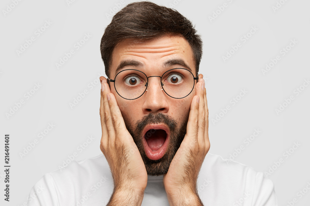 Close up portrait of handsome terrified young male with stubble being ...