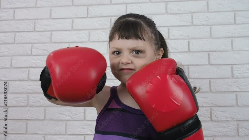 Child in boxing gloves. Aggressive little girl in boxing gloves is ...
