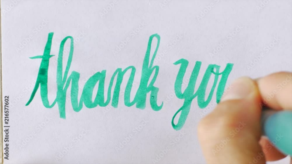 Hand writing the words THANK YOU in cursive with a green pen Stock ...