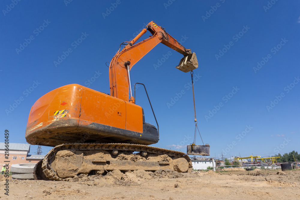 Excavator moves a concrete ring for a sewer well Stock Photo | Adobe Stock