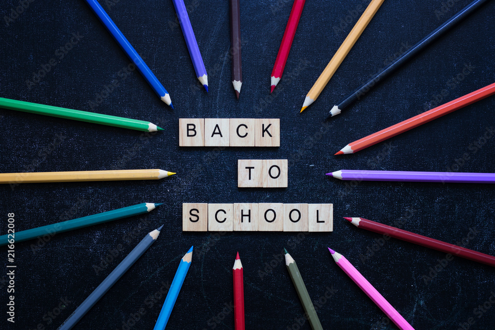 Coloured pencils around wooden words back to school on slate black ...