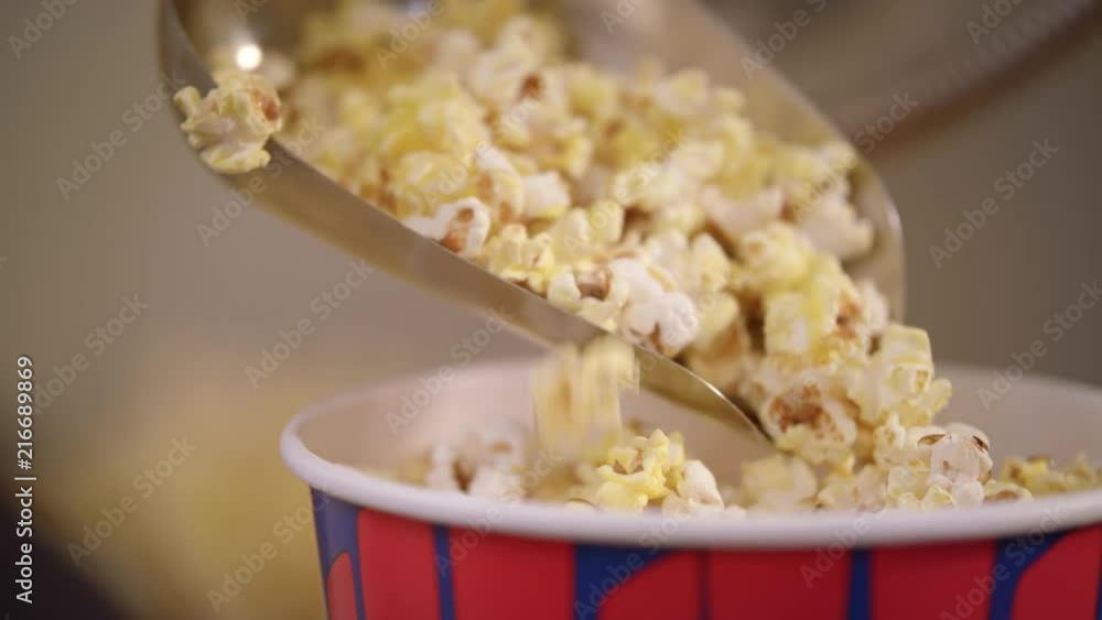 Popcorn flakes pouring by ladle to paper container in slow motion ...