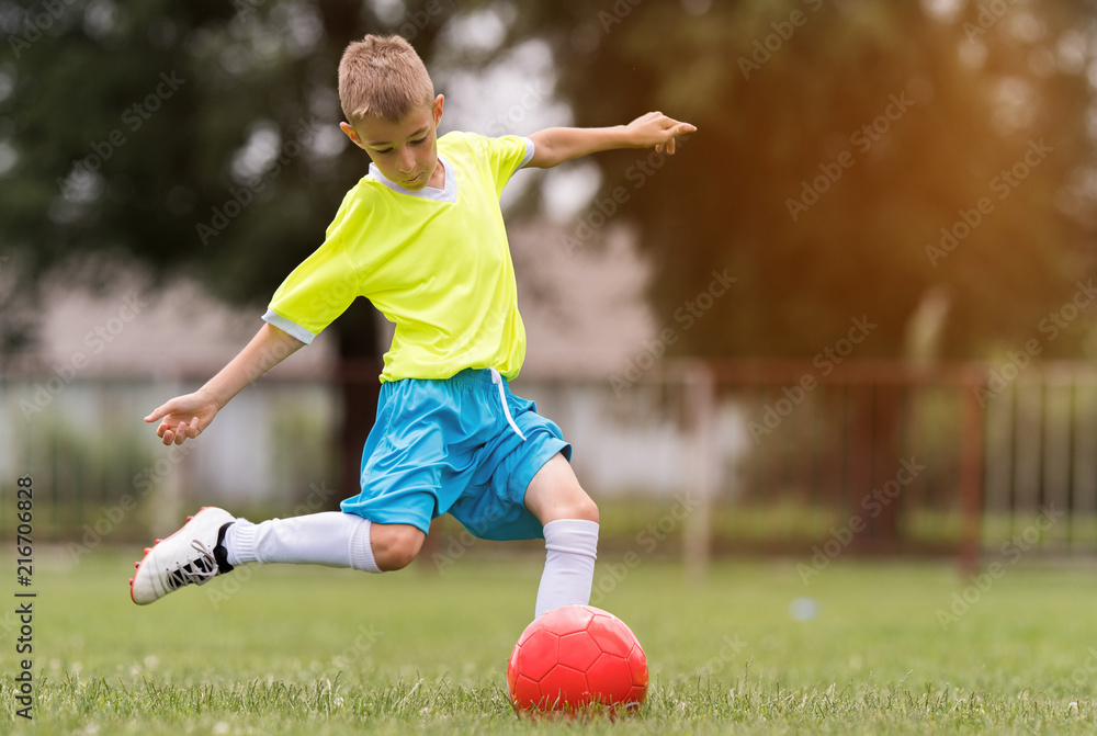 Boy kicking football on the sports field Stock Photo | Adobe Stock