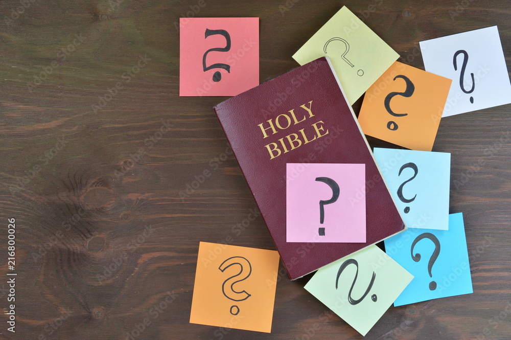 Holy bible and colorful note pads with question marks on brown wooden ...