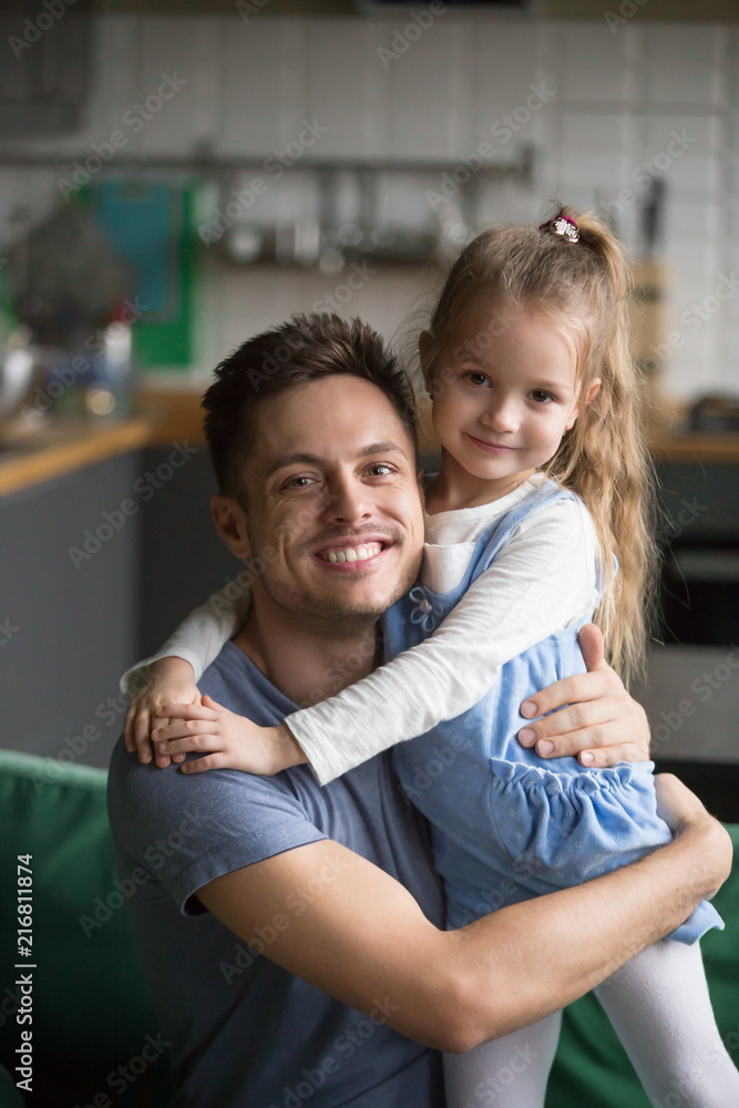 Vertical portrait of happy kid daughter embracing father at home, cute ...
