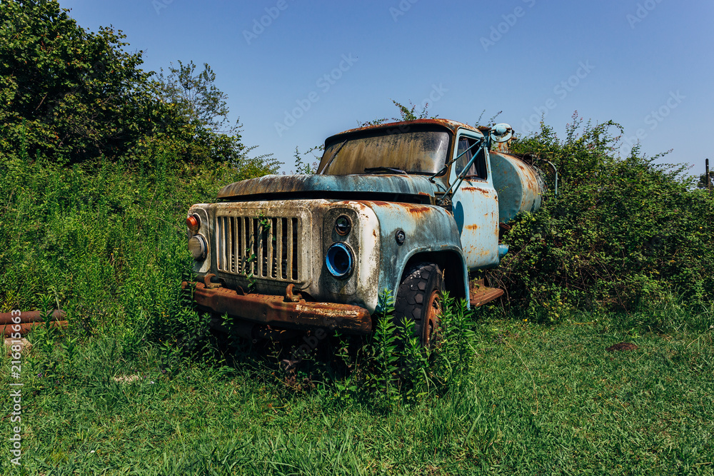 Old rusty overgrown truck. Abandoned Soviet tank car in ghost town ...