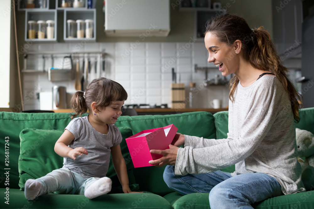 Smiling mom giving excited daughter present on her birthday, happy ...