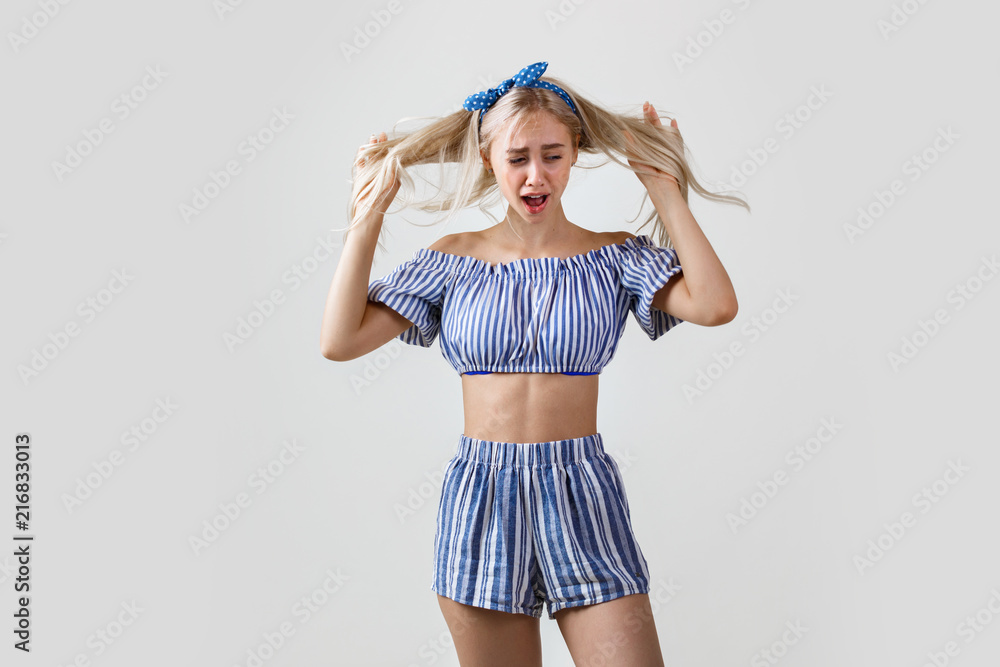 Beautiful blonde girl in summer outfit is holding hands on head crying ...