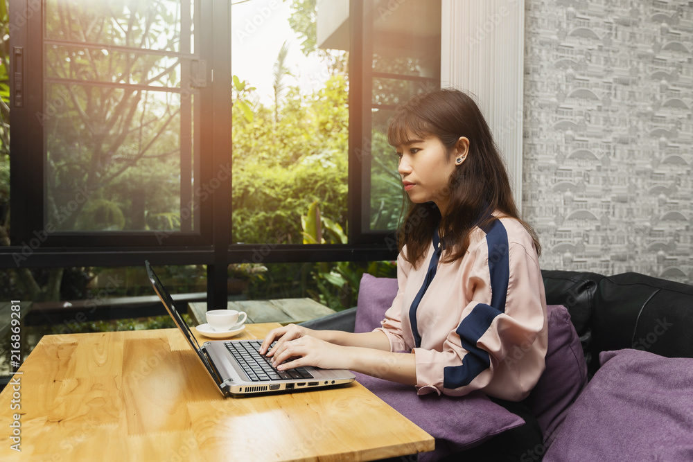 Beautiful young Asian woman using laptop computer while sitting in a ...