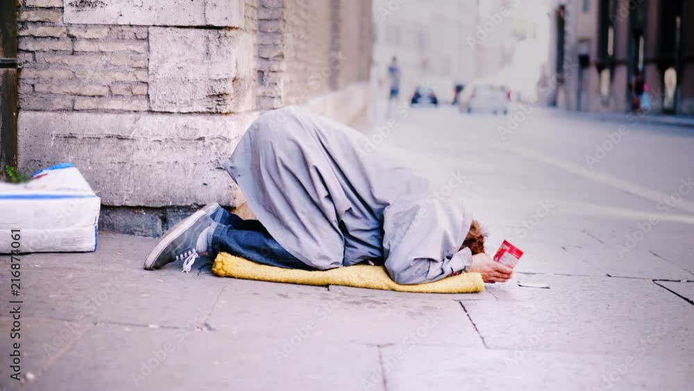 A homeless man begging begs for alms standing on his knees and lower ...