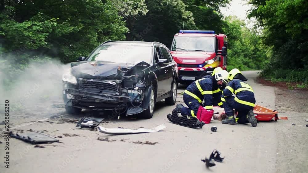 Firefighters rescuing a young injured woman lying on the road after an ...