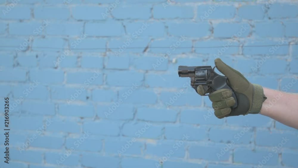 Man in green military strategic gloves with short-barreled revolver ...