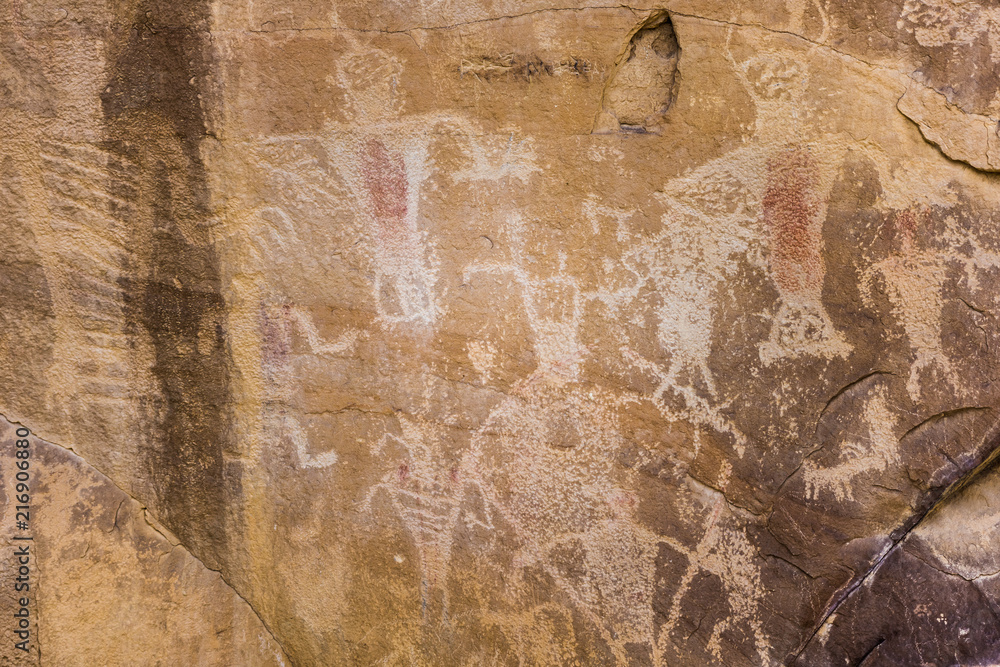 Cluster of ancient rock wall carvings depicting people and animals ...