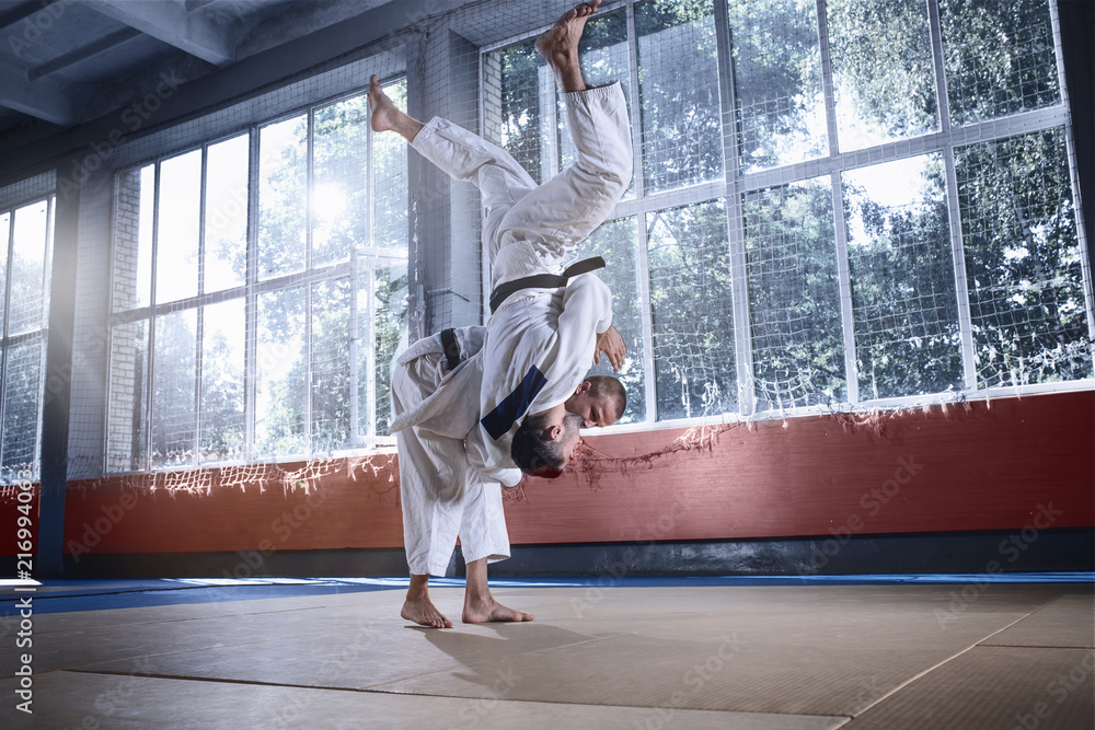 Two judo fighters showing technical skill while practicing martial arts in a fight club. The two ...