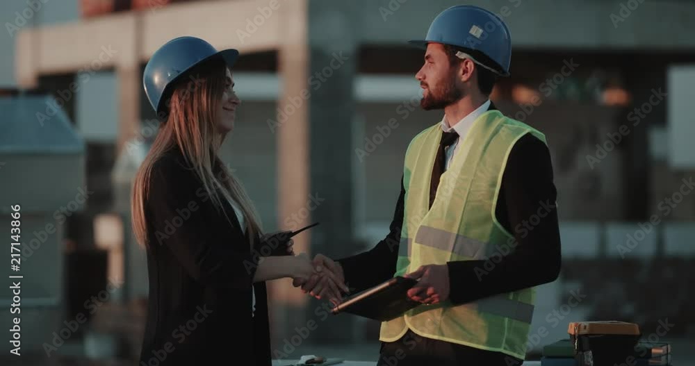Two young partner female and man making at deal at construction site ...