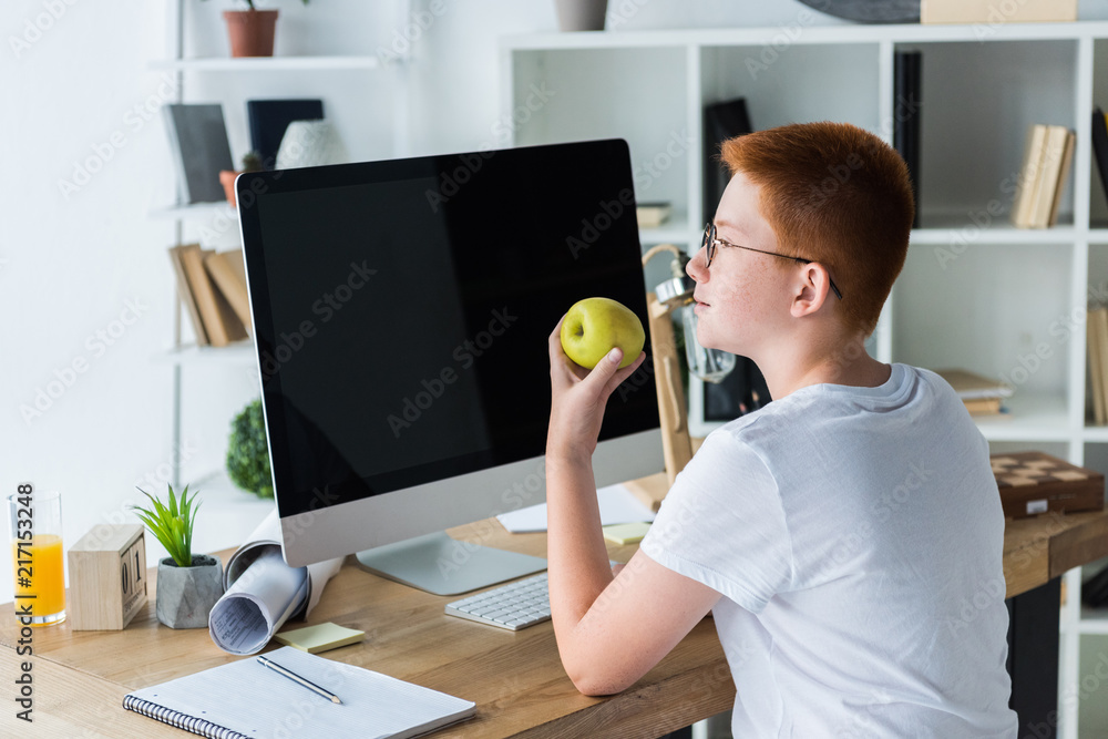 preteen ginger hair boy holding apple near computer at home Stock Photo ...